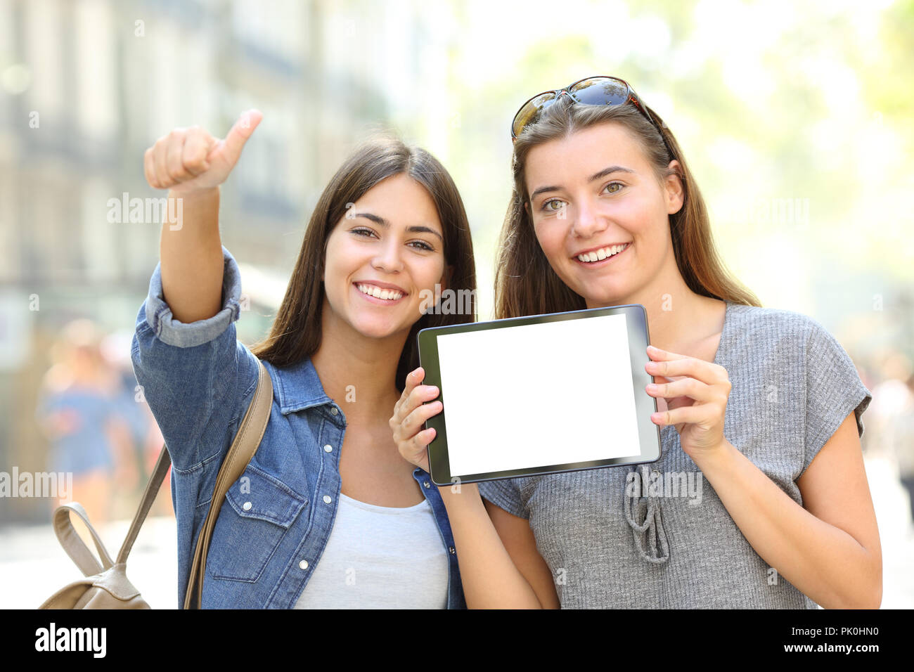 Front view portrait of a positive friends showing a blank tablet screen ...