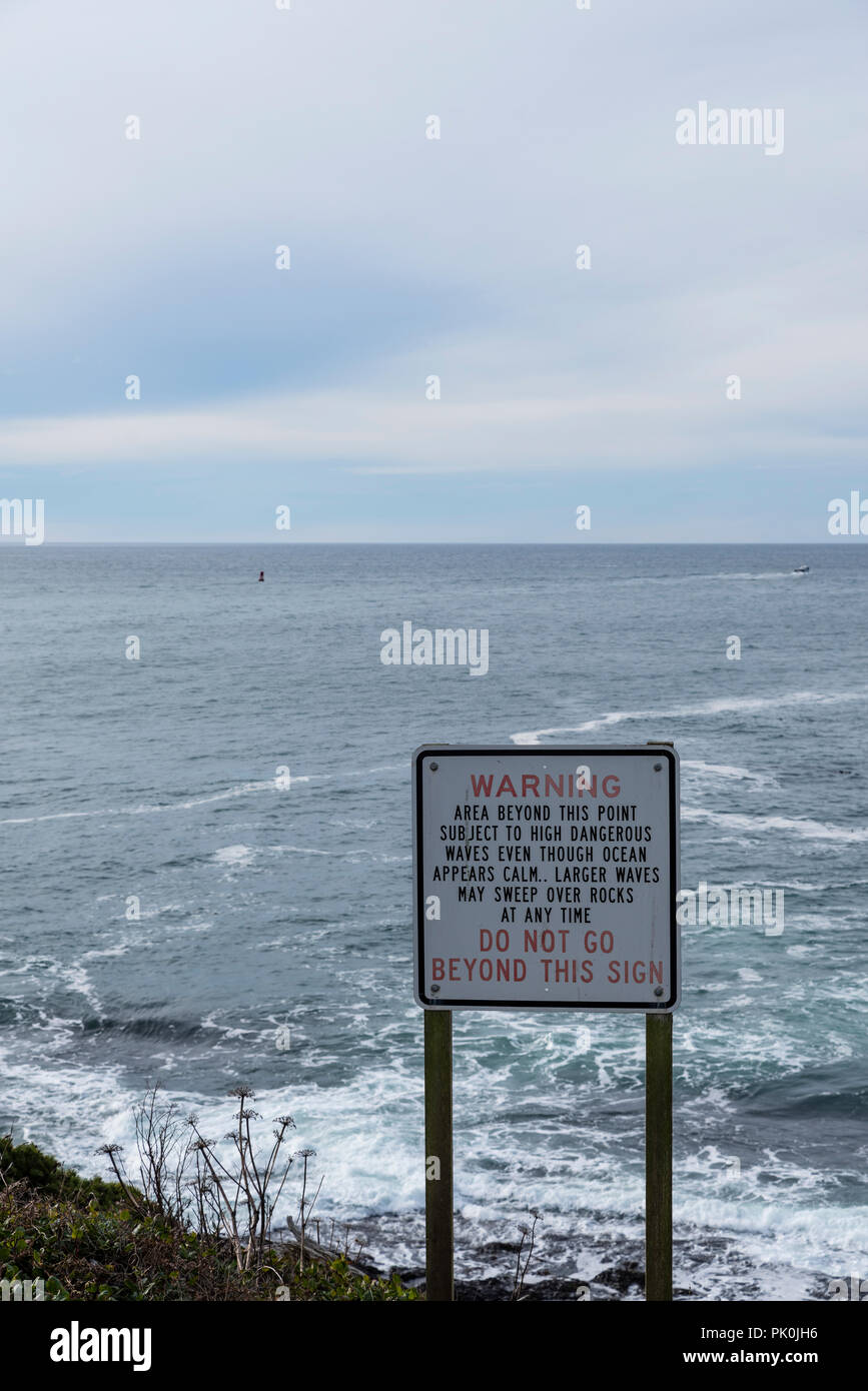 Warning sign on the beach at Depot Bay advises of high, dangerous waves ...