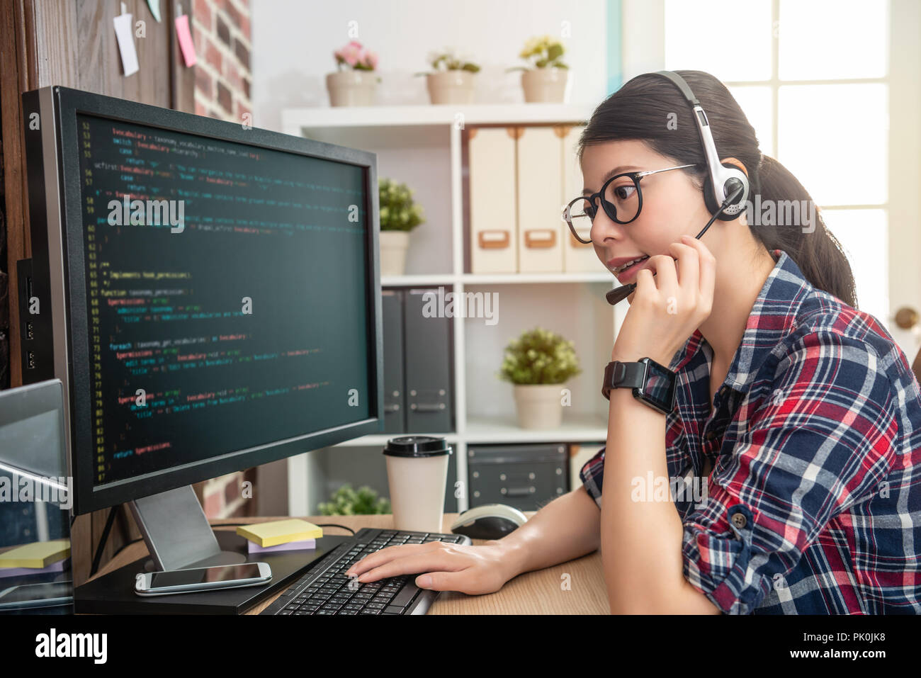 female programmer speaking to customer thru headphone and smiling ...