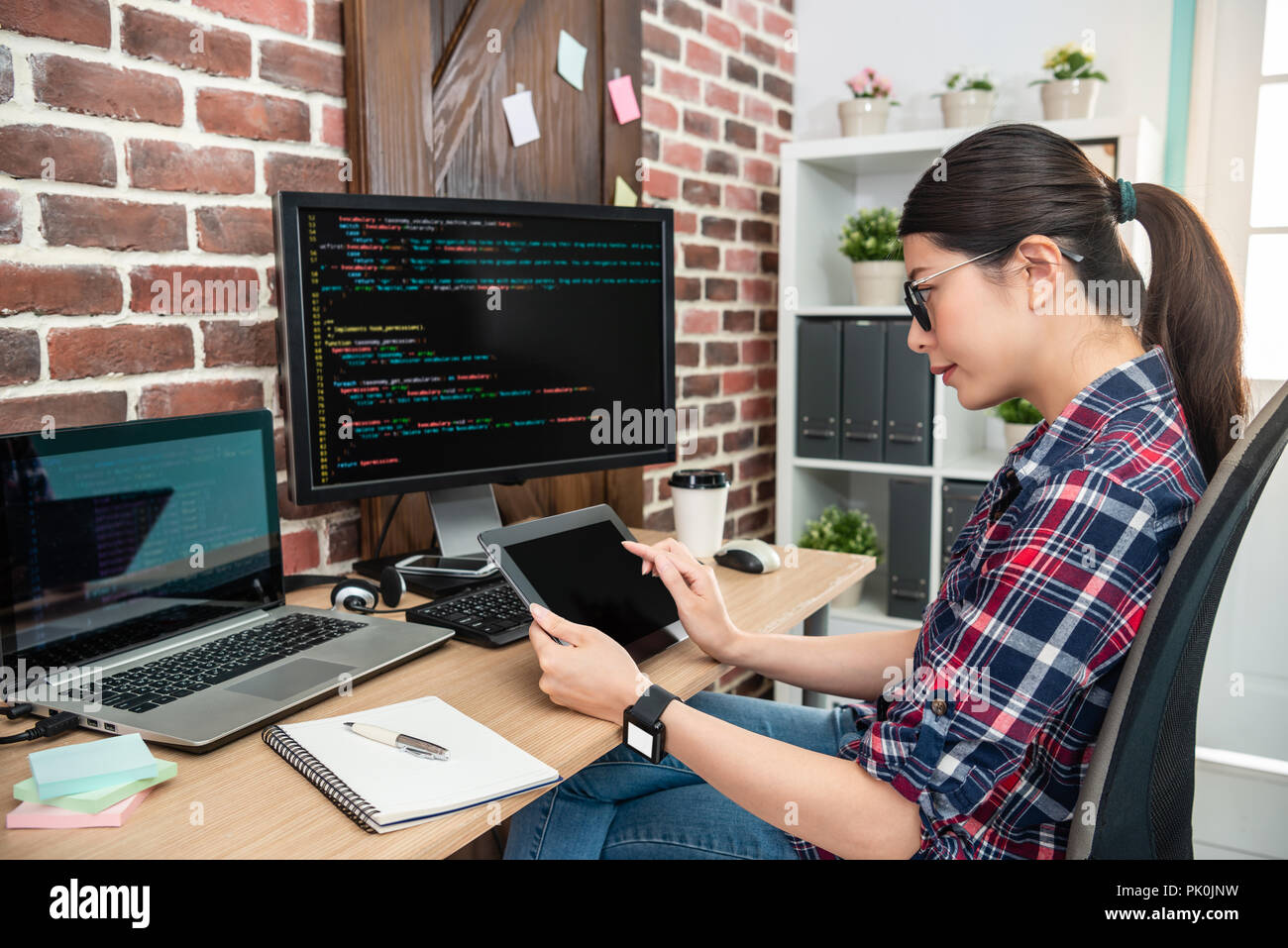 portrait of a female programmer touching the screen of tablet sitting ...