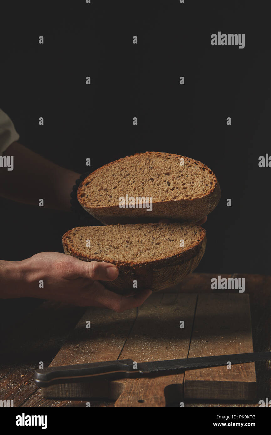 the man baker holds in his hands halves of rye bread, against the ...