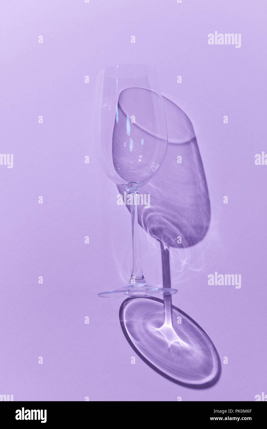 Wine glass in a snifter casting a shadow over a purple background ...