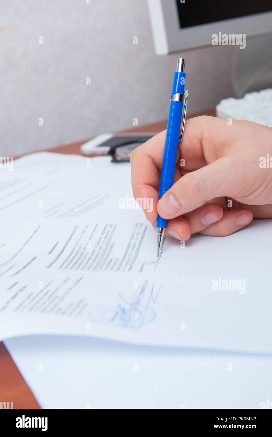 Hand with pen on desk signs documents Stock Photo - Alamy