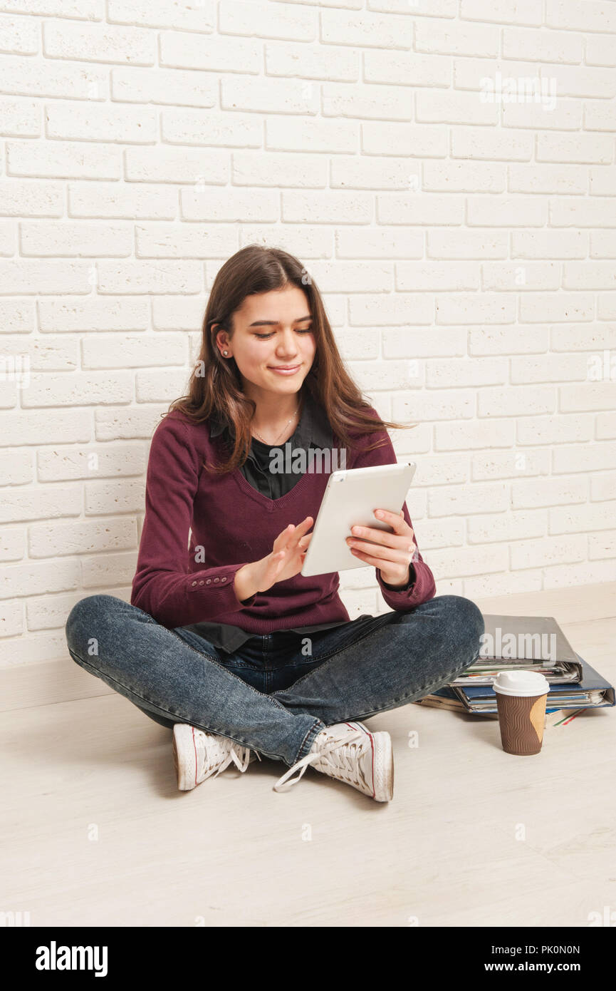 girl student sitting on the floor against a brick wall Stock Photo - Alamy