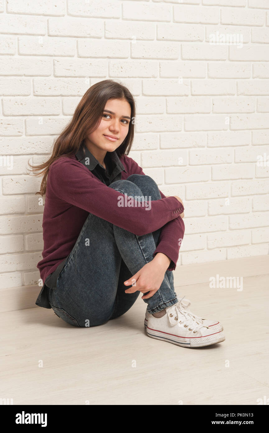 Sad girl sitting against wall hi-res stock photography and images - Alamy