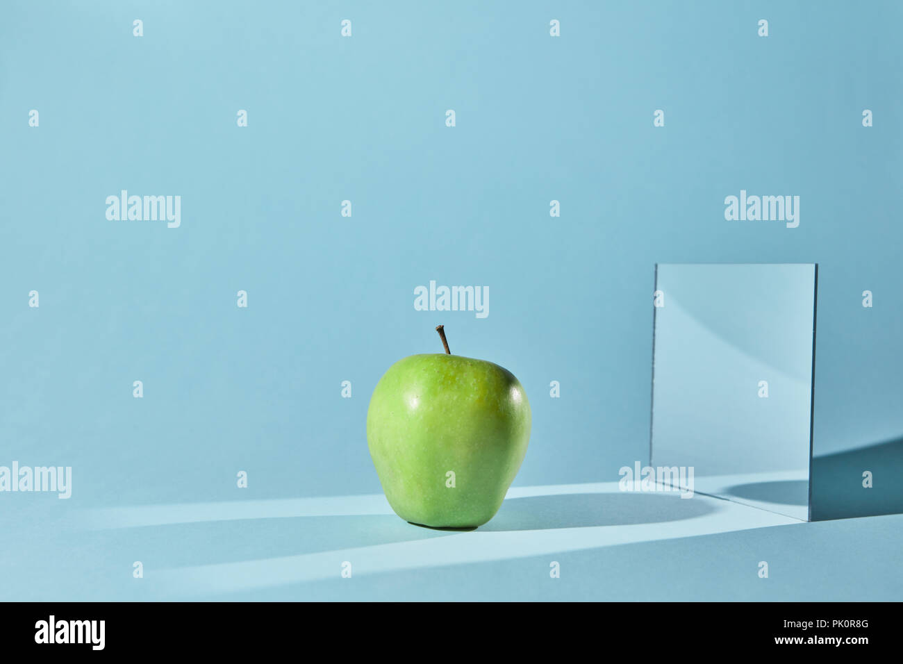 Reflection of the shadow from apple in a mirror. Diagonal long shadows ...