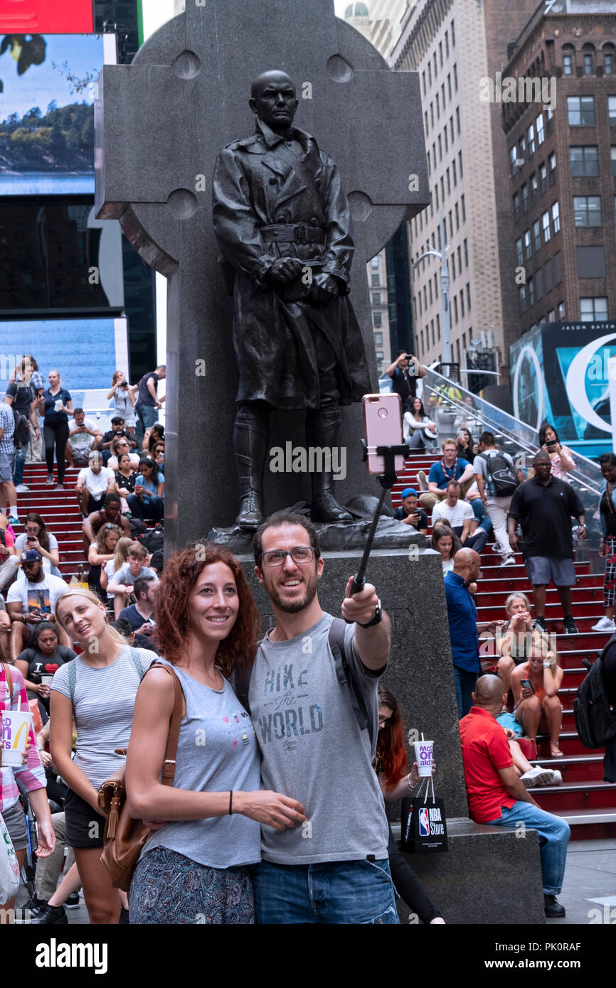 Tourists in Times sSquare take a selfie in front of the statue of ...