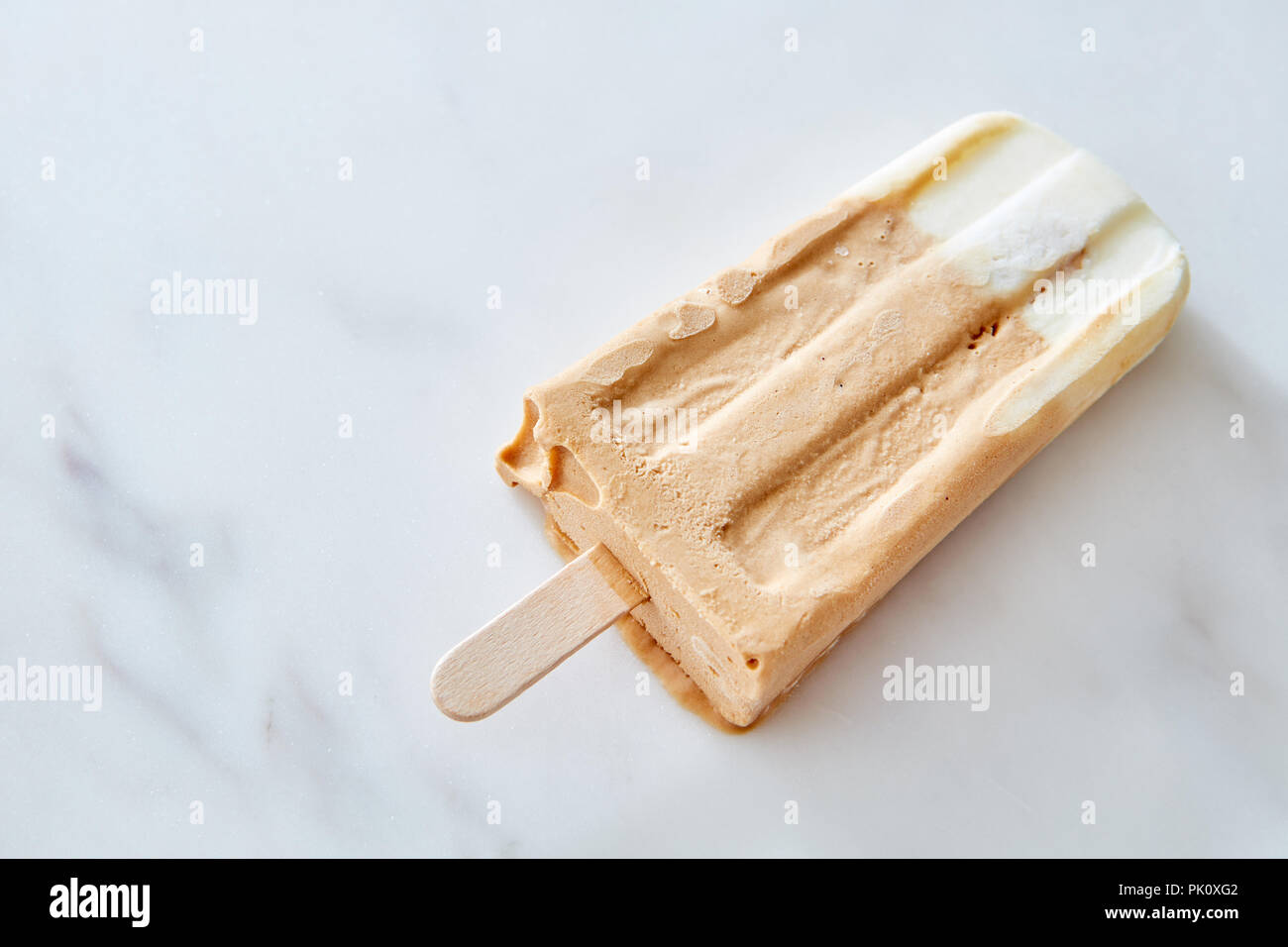 Homemade refreshing iced coffee popsicles on a stick against a marble ...