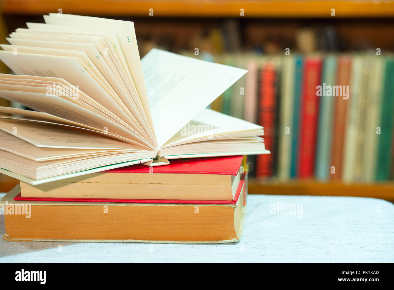 Open book, stack of hardback books on table. Back to school. Copy space ...