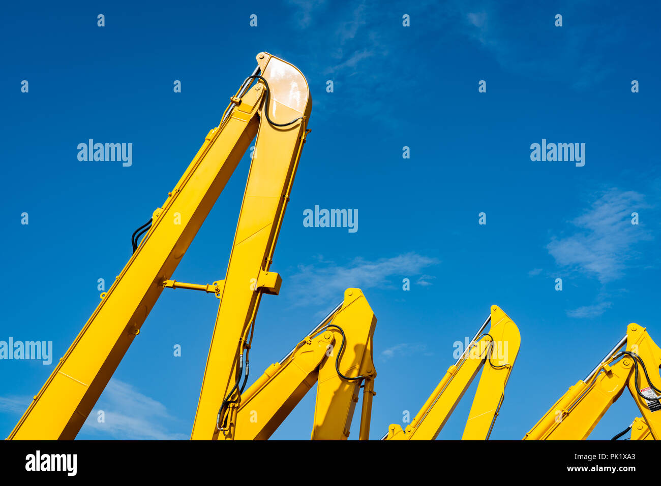 Yellow backhoe with hydraulic piston arm against clear blue sky. Heavy ...
