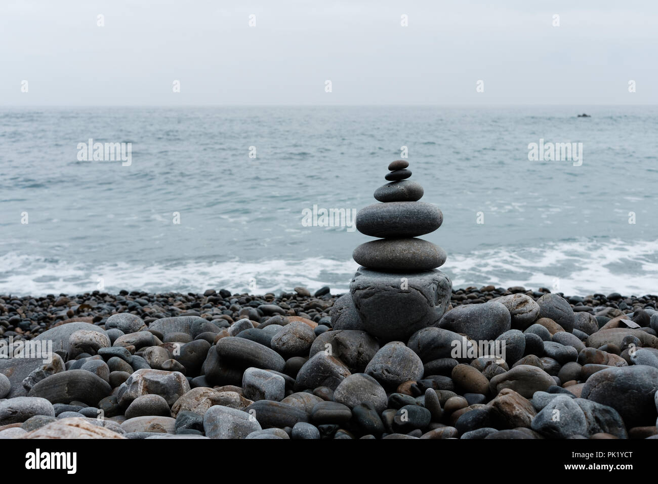 Stack of pebbles on a big rock at the beach on the ocean background ...