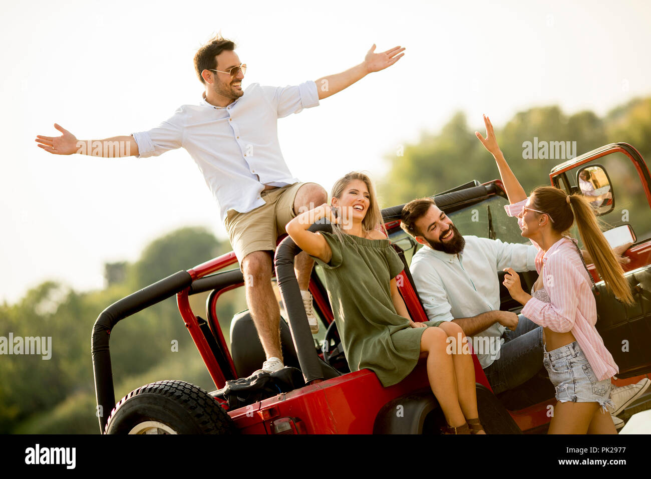 Happy friends having fun in convertible car at vacation by river Stock ...