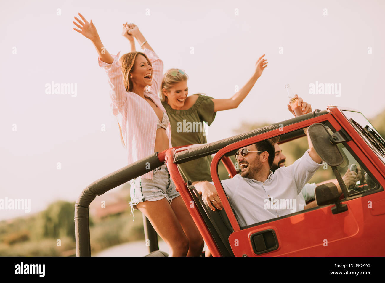 Happy friends having fun in convertible car at vacation by river Stock ...