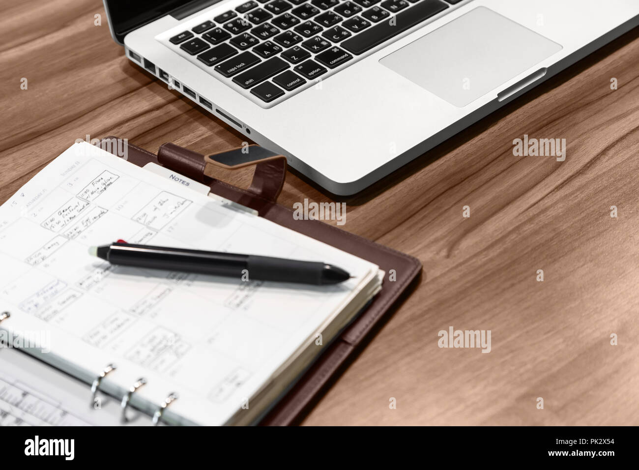 Office desktop. On the desk is a laptop, a notebook with notes and a ...