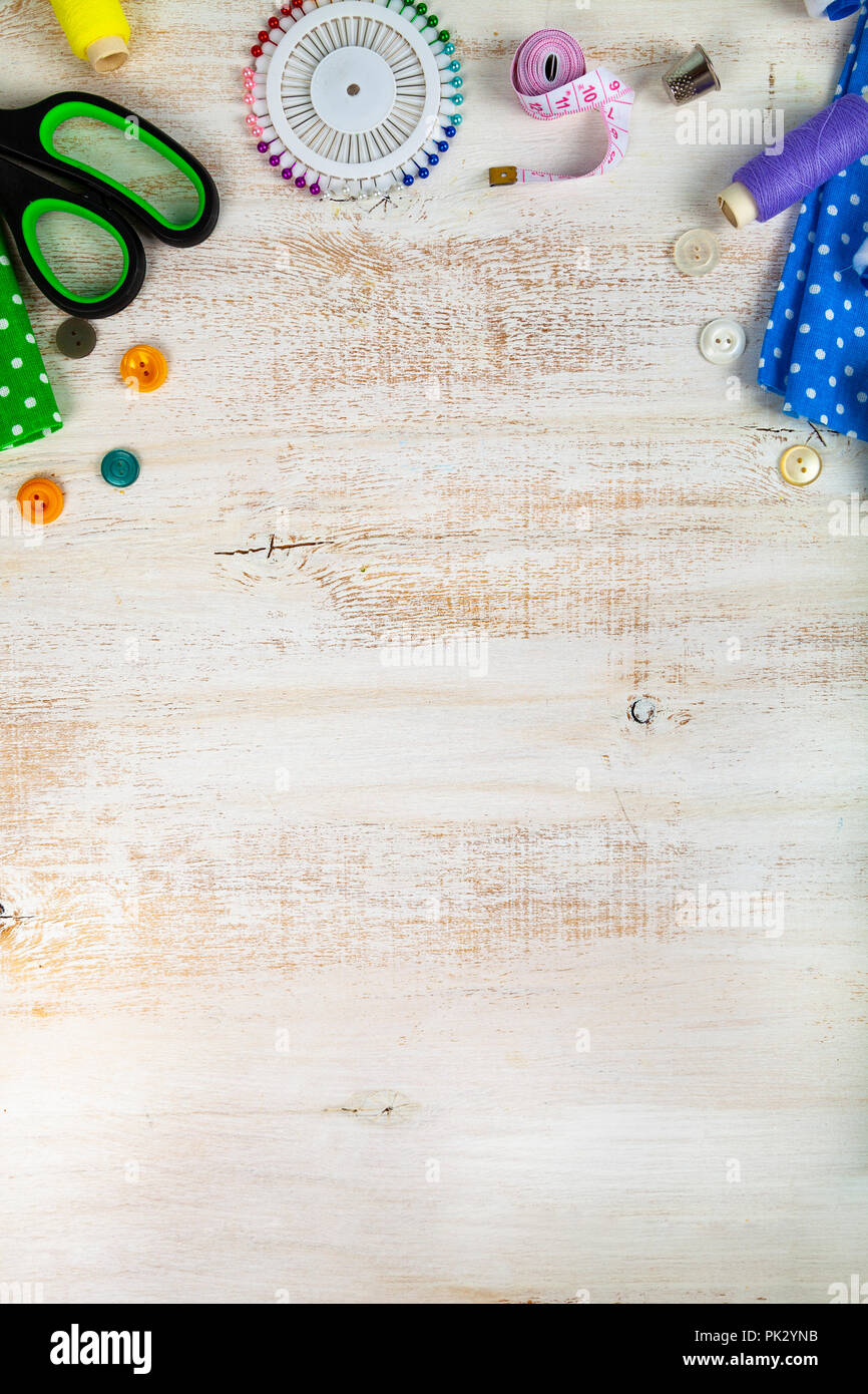 Sewing accessories and fabrics on a wooden background. Border of thread ...