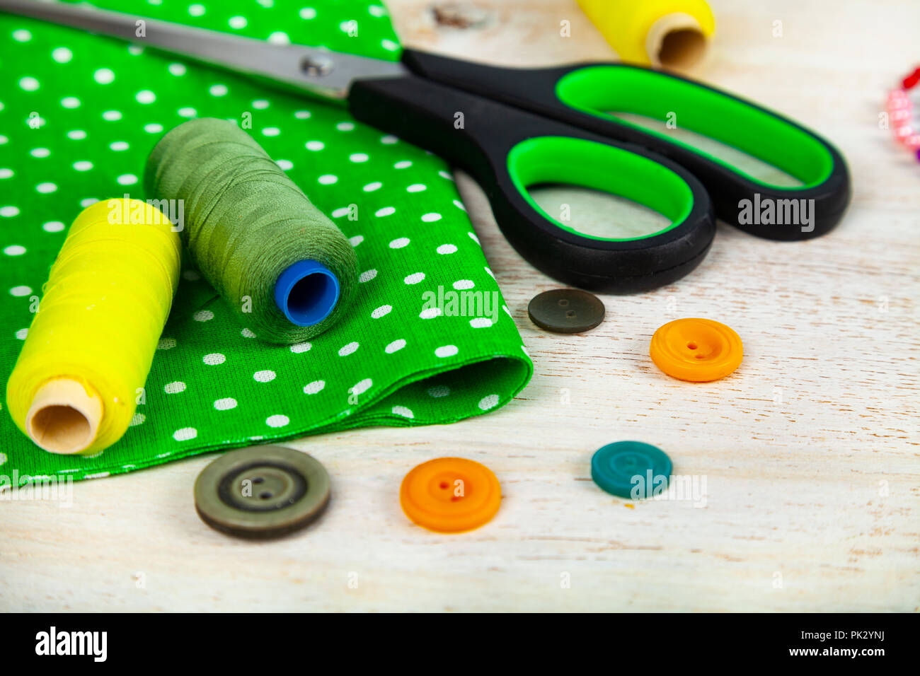 Sewing accessories and green fabric on a wooden background. Fabrics ...