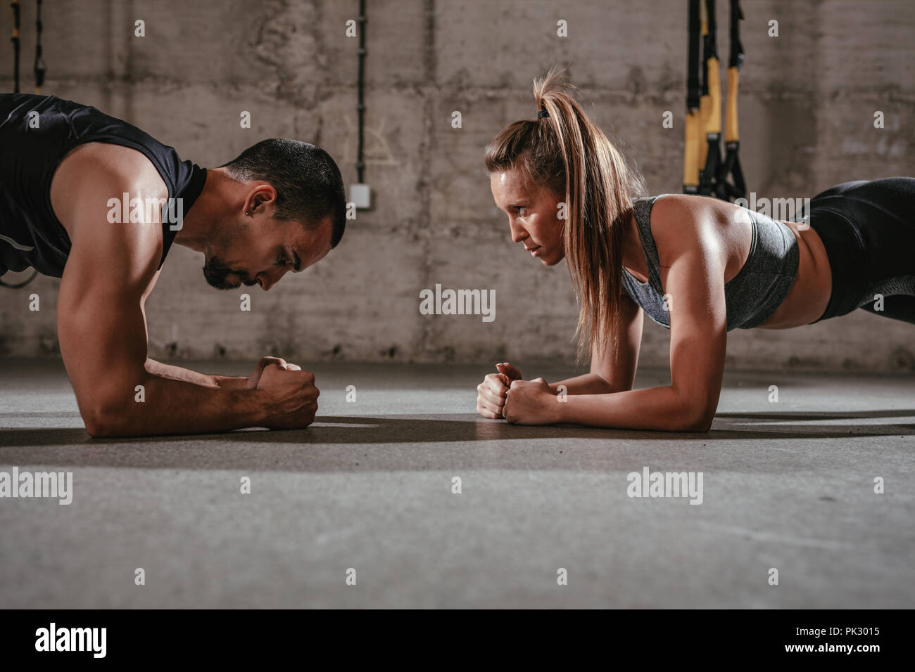 Young muscular couple doing push-up exercise at the cross fit workout ...
