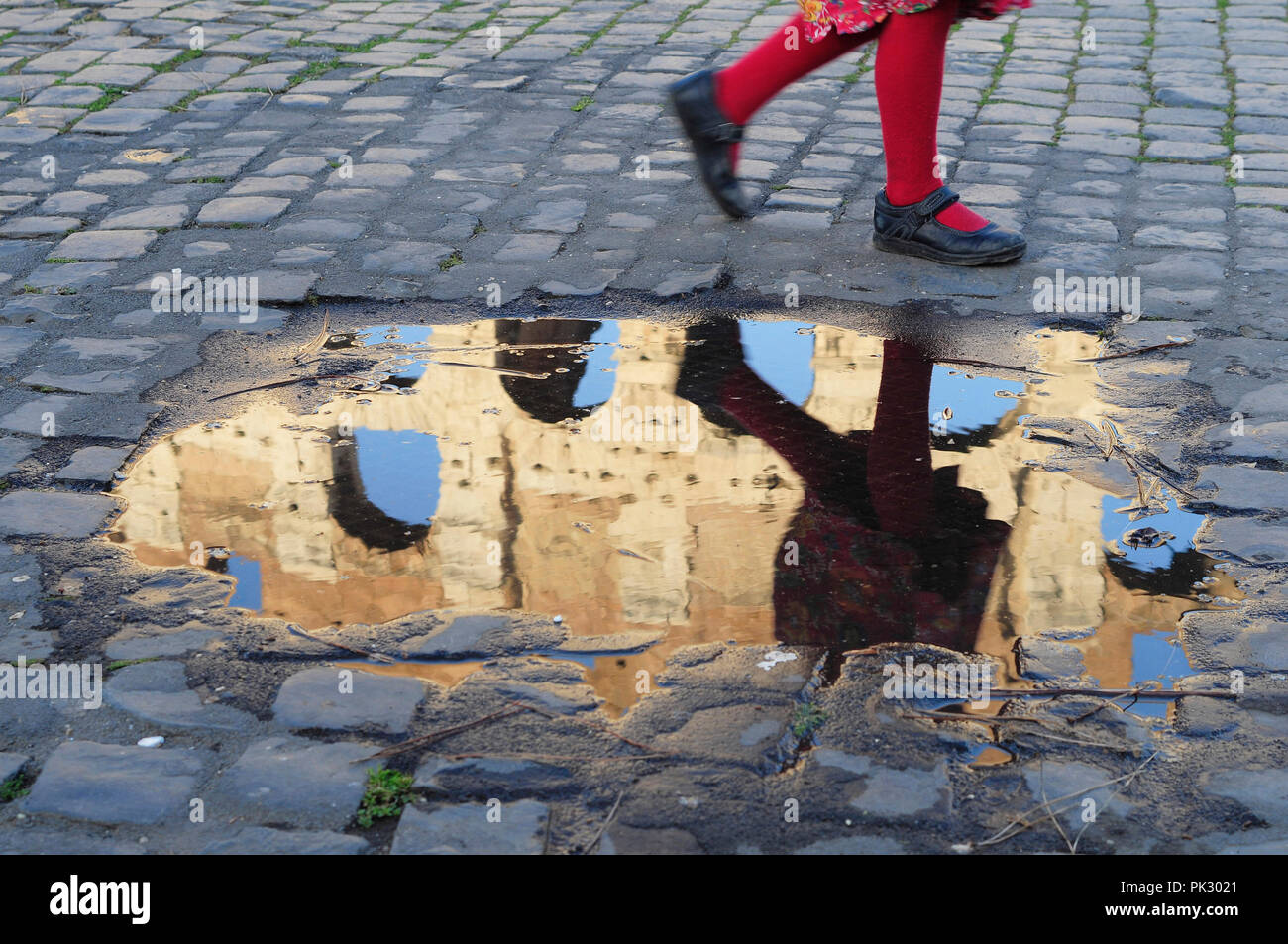 Italy, Lazio, Rome, Colosseum, girl running past puddle with reflection ...