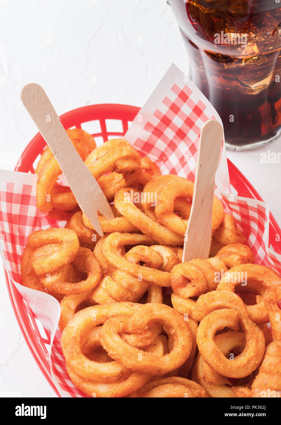 Curly fries fast food snack in red plastic tray with glass of cola on ...
