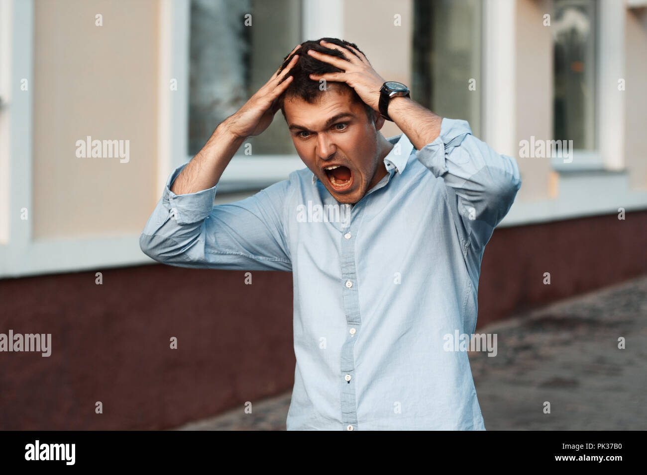 Portrait of young angry man with hands on head. Clings to his head and ...