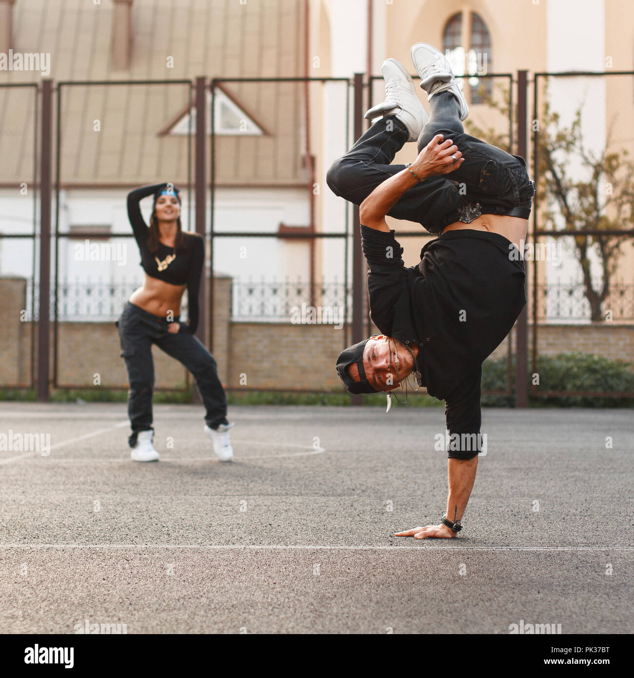 The young dancer standing on his hand. Dancing hip hop with a beautiful ...