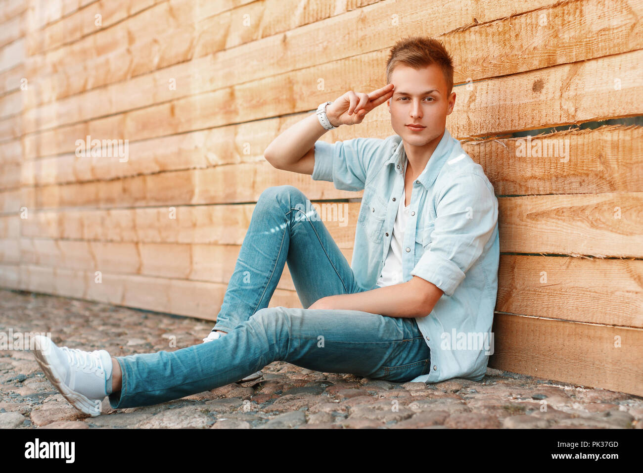 Young man posing by the wooden wall. Guy saluting Stock Photo - Alamy