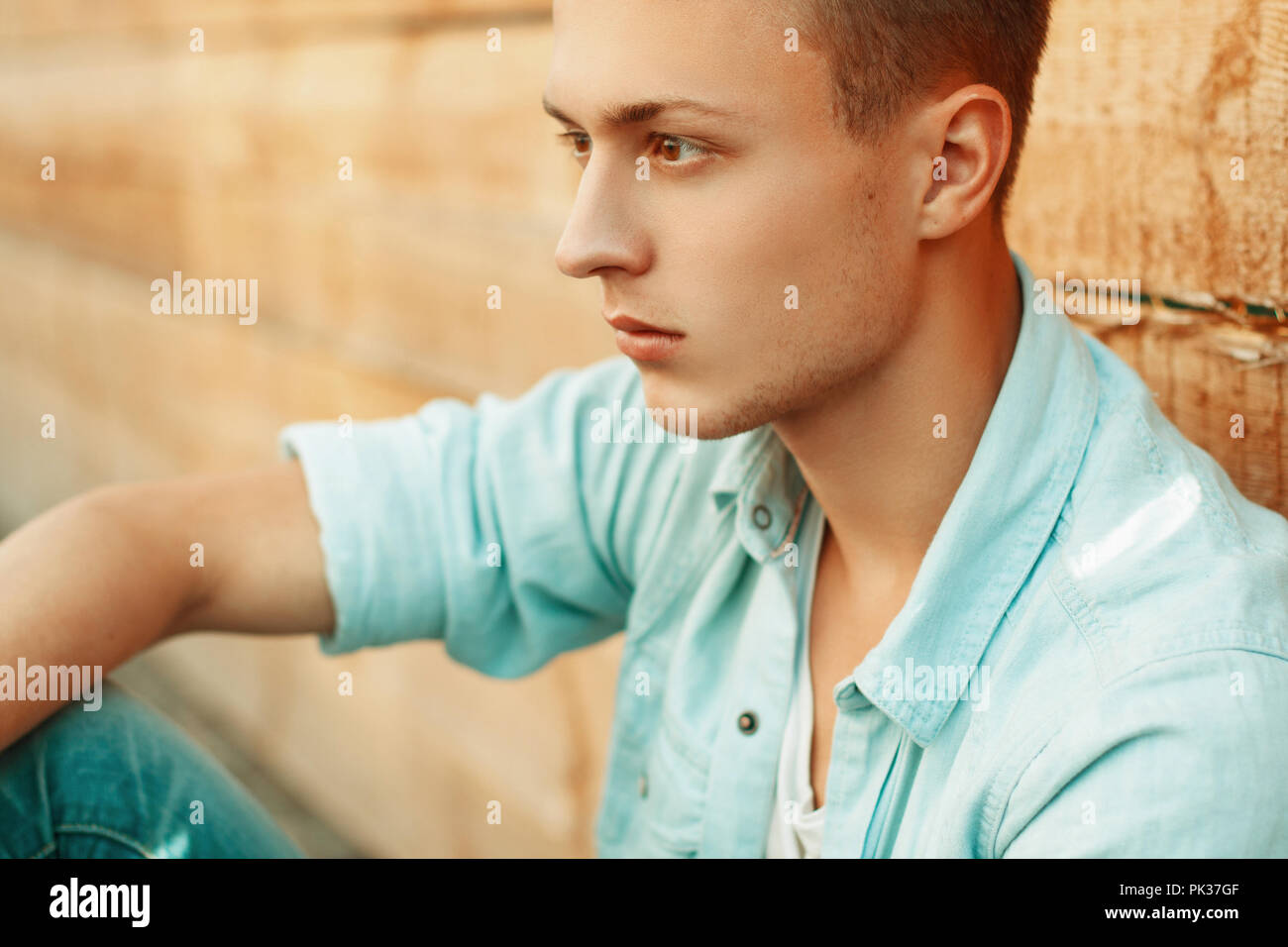 Young sad man in denim clothes on the background of wooden wall Stock ...
