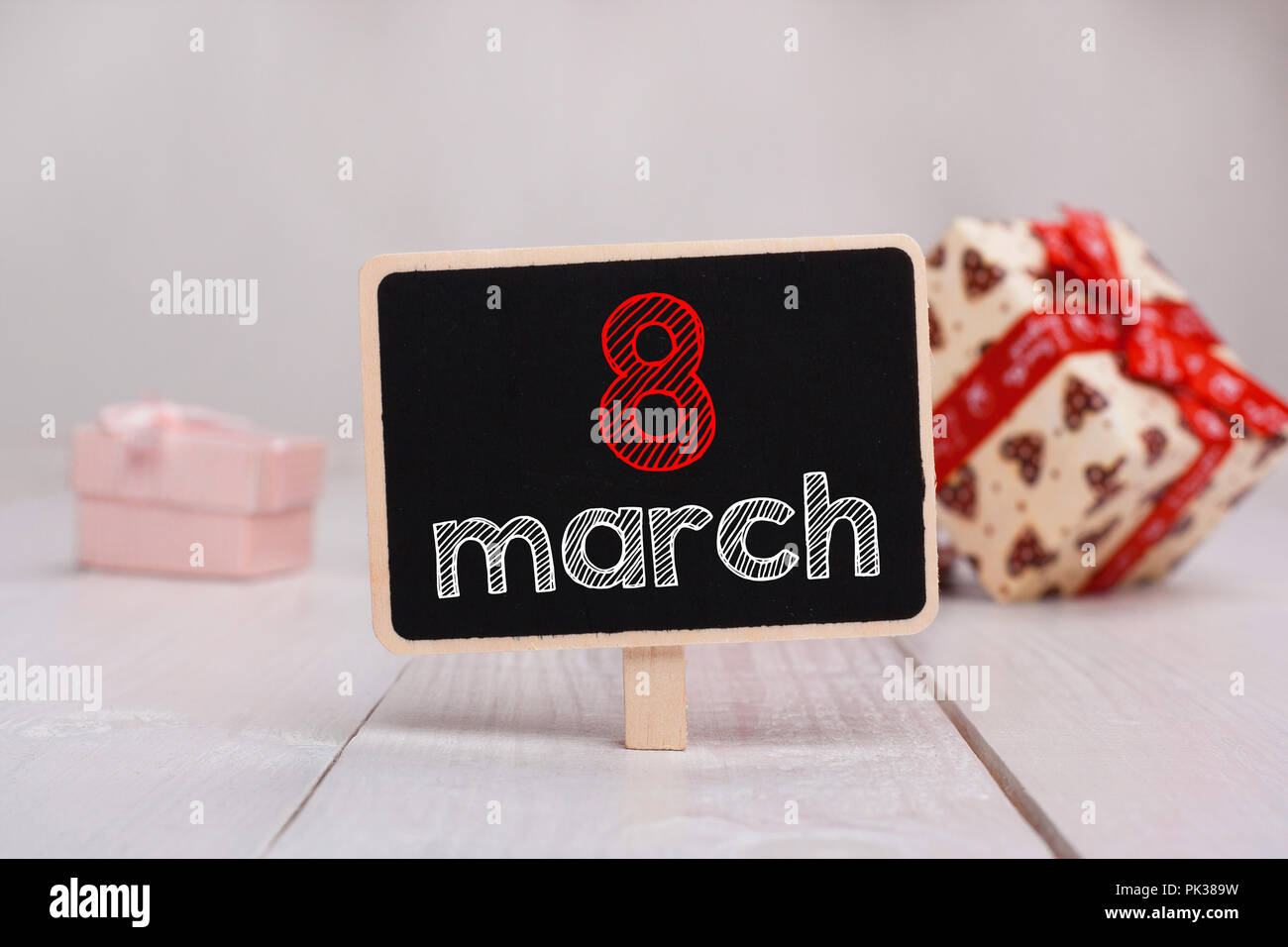 8 March message written on little chalkboar. Background with gifts ...