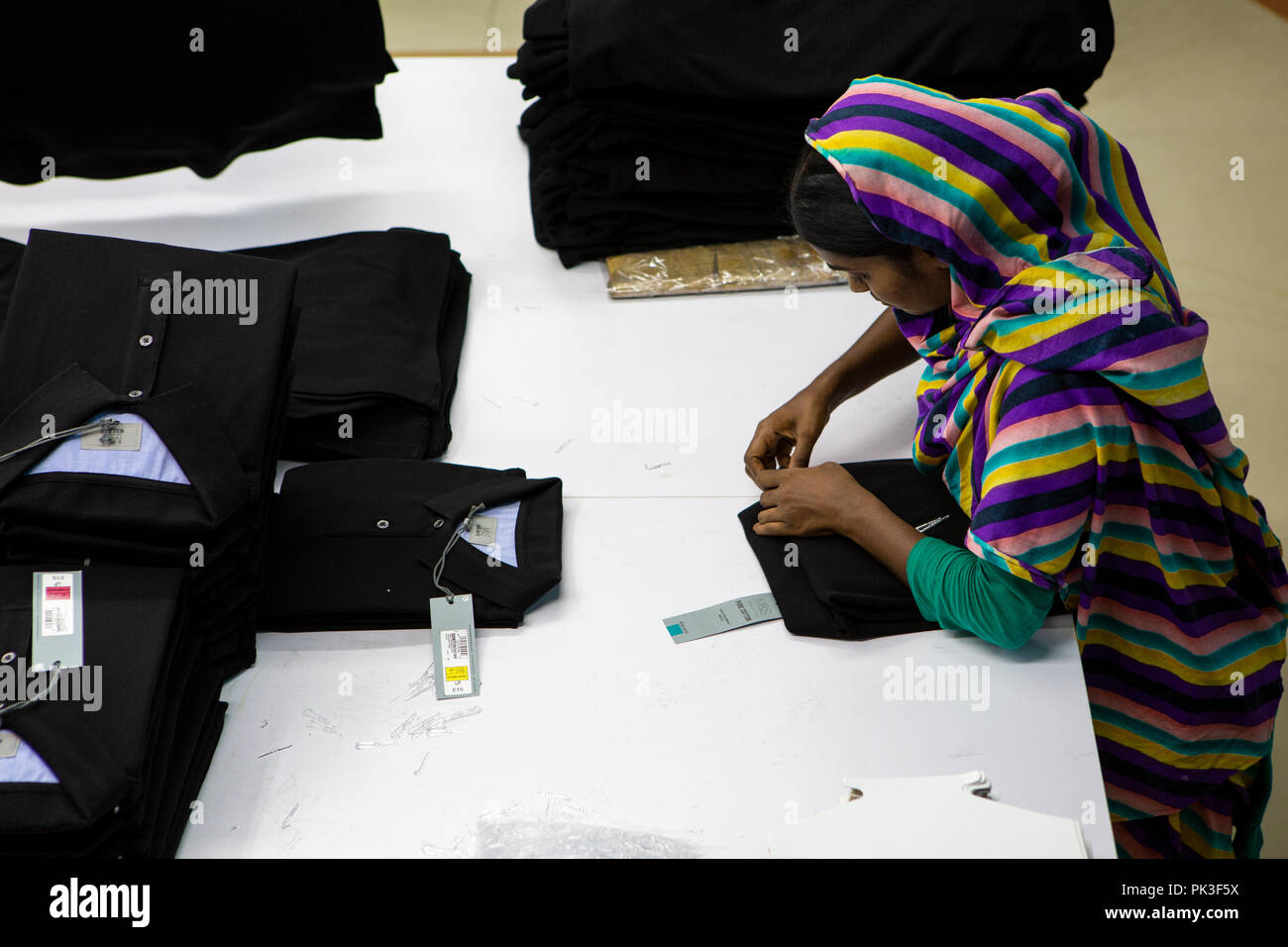 A garment worker folding clothes inside a garment factory in Bangladesh ...