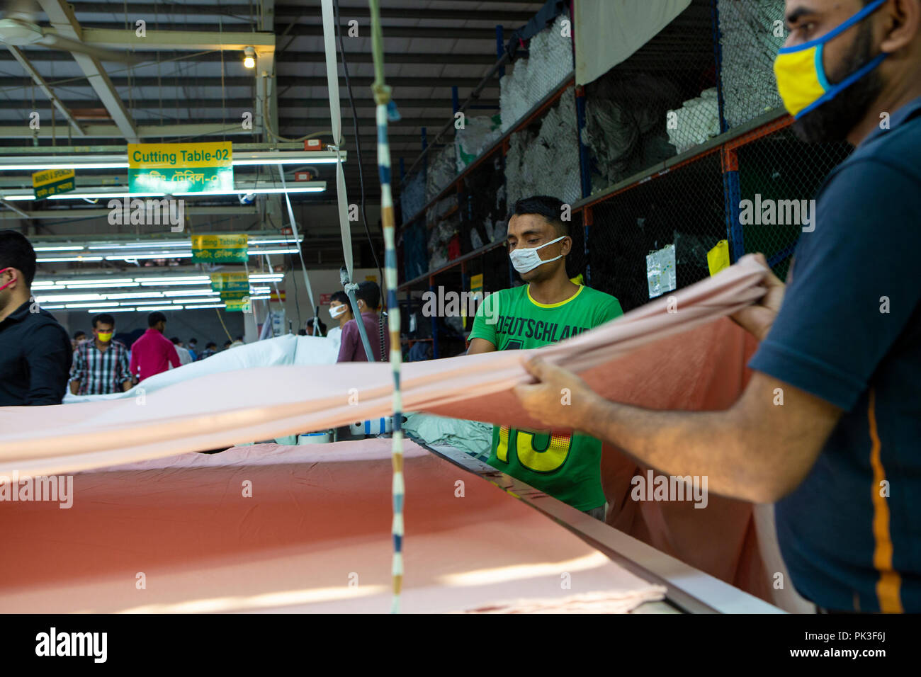 Garment workers measuring and cutting lengths of material inside a ...