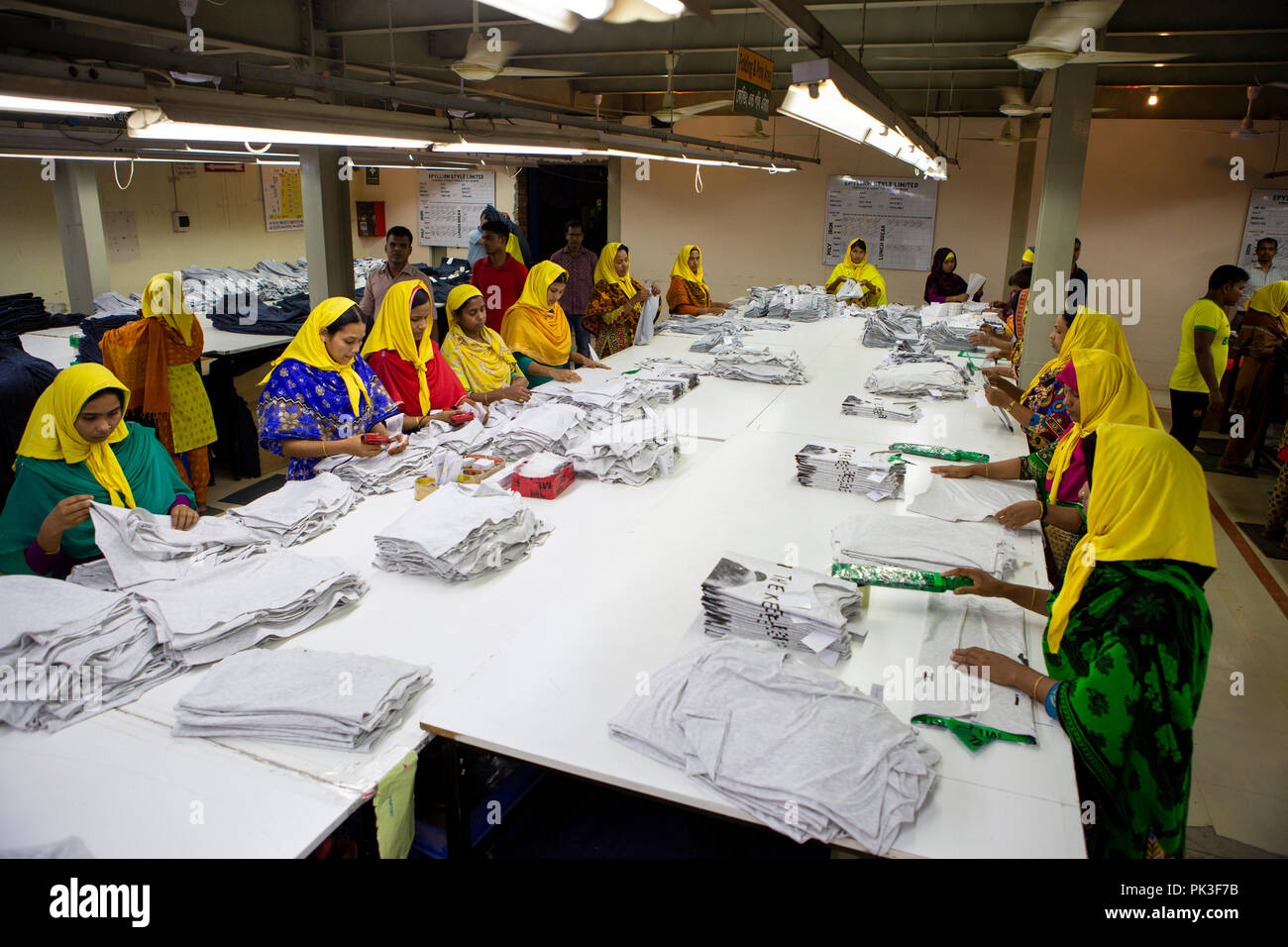 A group of female garment workers folding clothes inside a garment ...