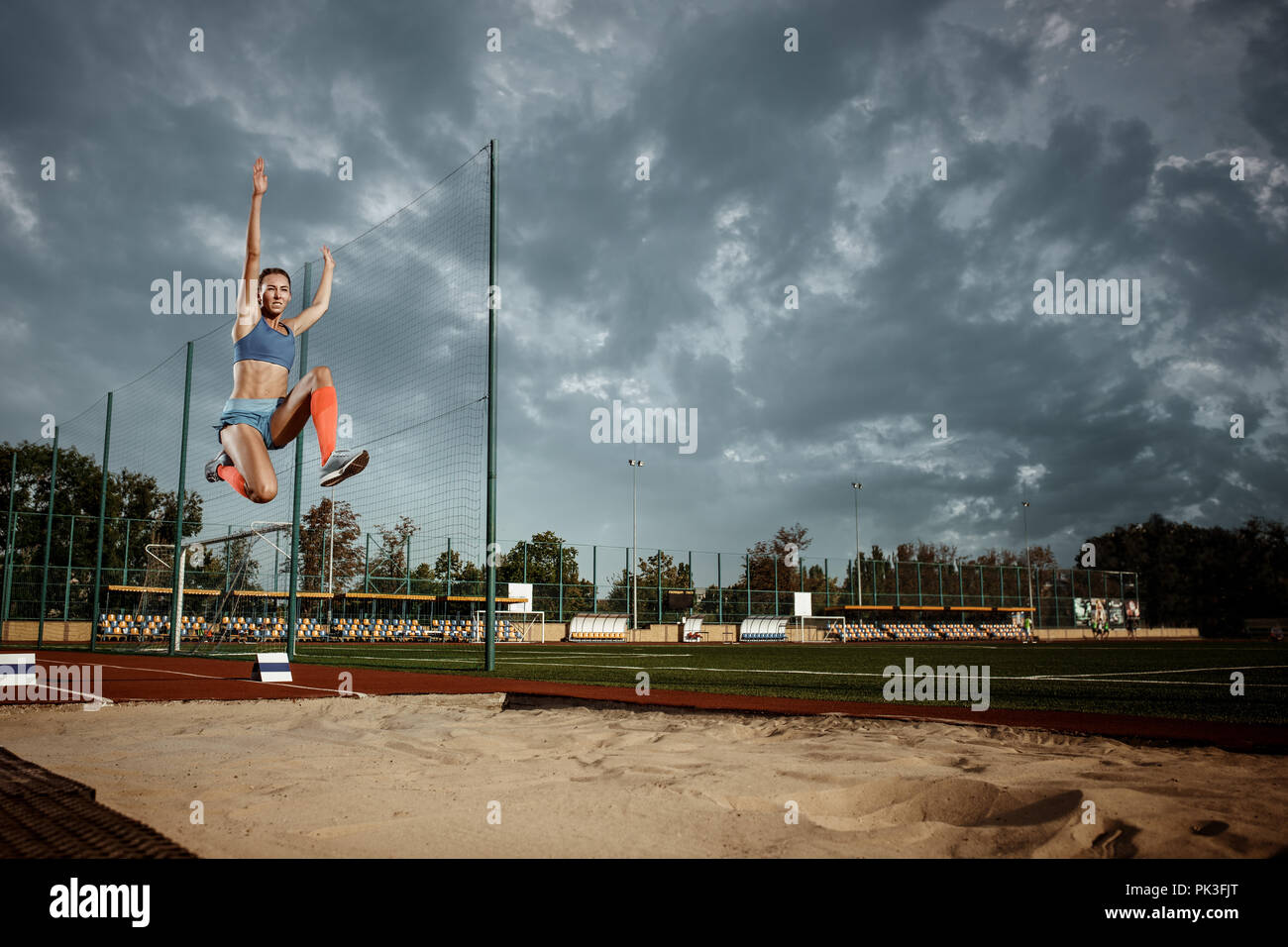 Female athlete performing a long jump during a competition at stadium ...