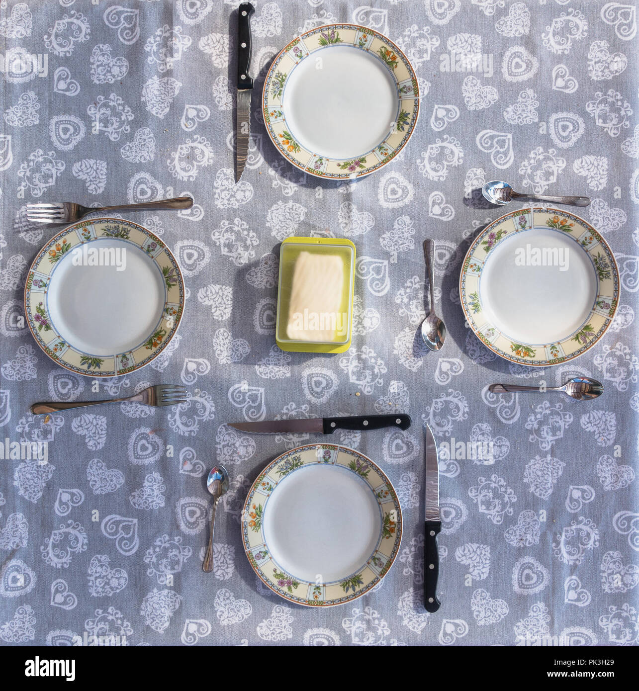 Wrong table set, dishes, four plates with forks, knifes, margarine ...