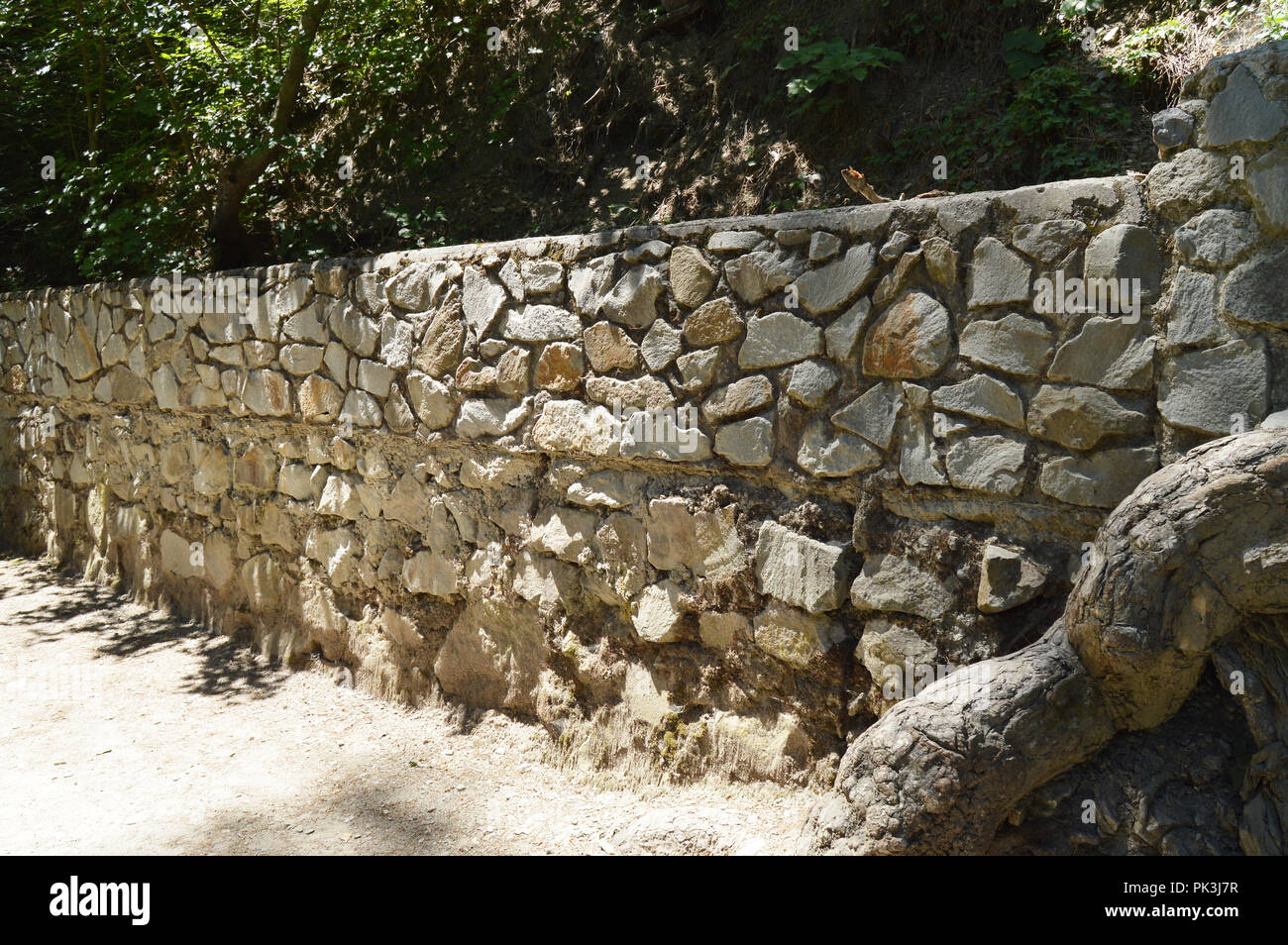 High stone fence along the pedestrian rural path in summer Sunny day ...