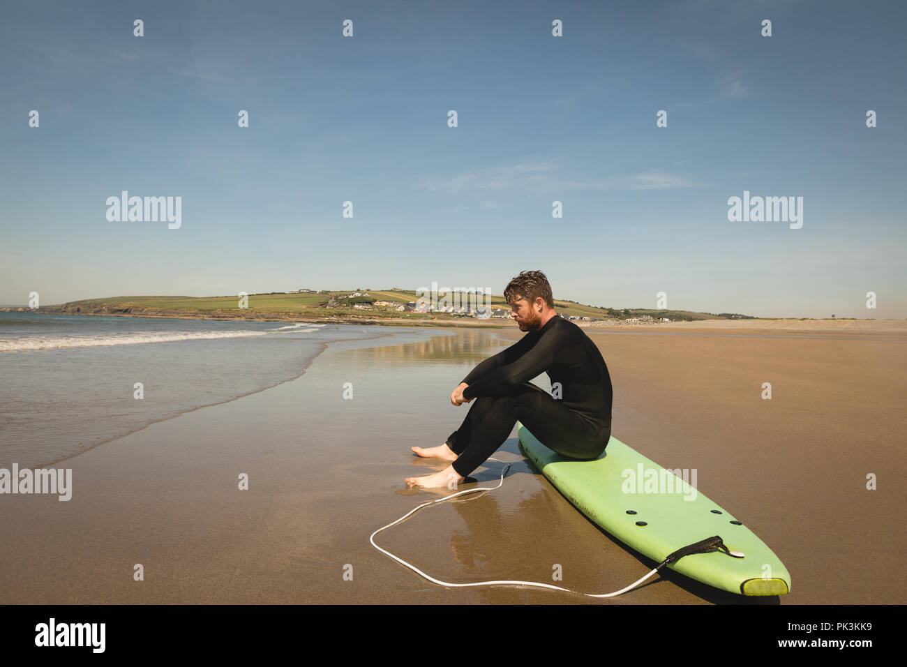 Surfer sitting on surfboard at beach Stock Photo - Alamy