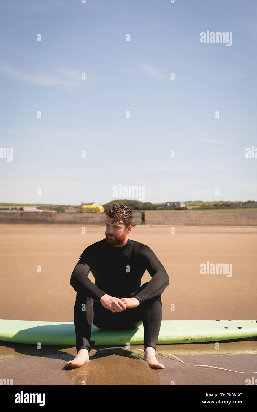 Surfer sitting on surfboard at beach Stock Photo - Alamy