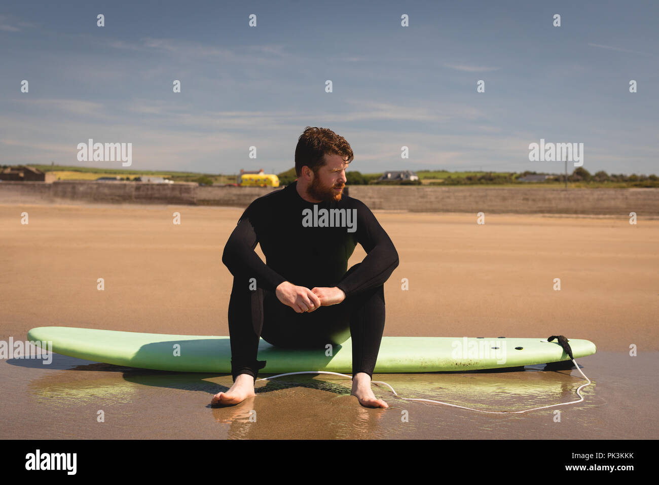 Surfer sitting on surfboard at beach Stock Photo - Alamy