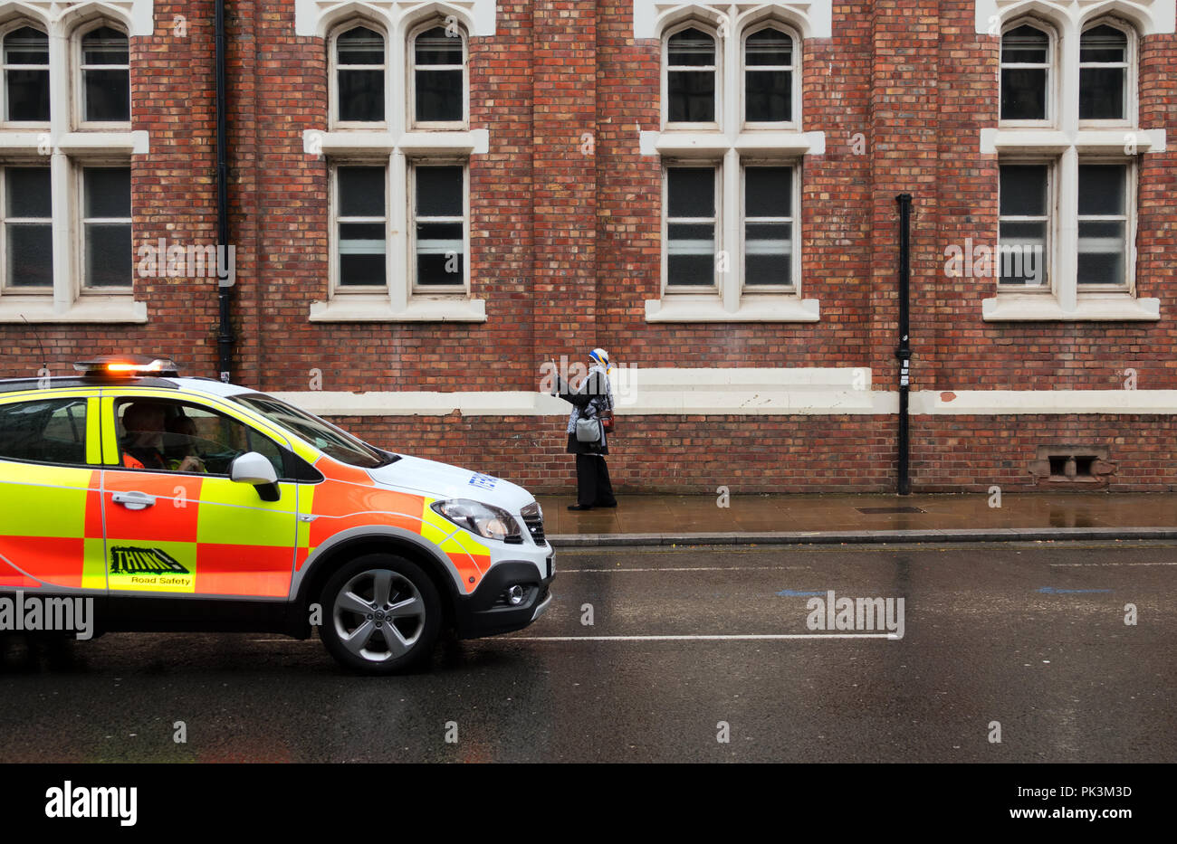 A black woman takes a selfie on her ipad as a police car passes by ...