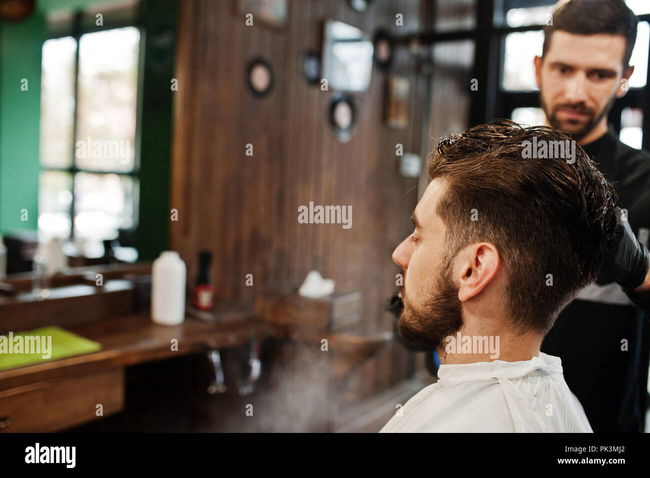 Handsome bearded man at the barbershop, barber at work, using hair ...