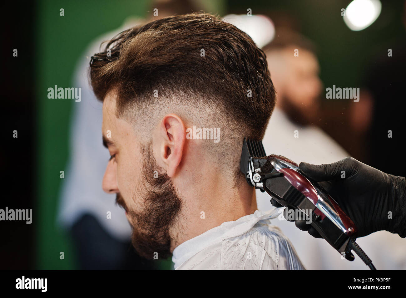Handsome bearded man at the barbershop, barber at work. Close up nape ...