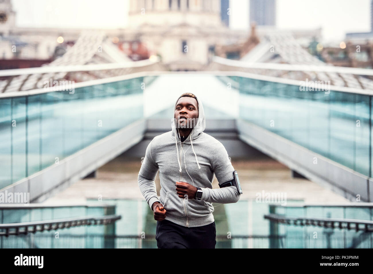 Young sporty black man runner running on the bridge outside in a city ...
