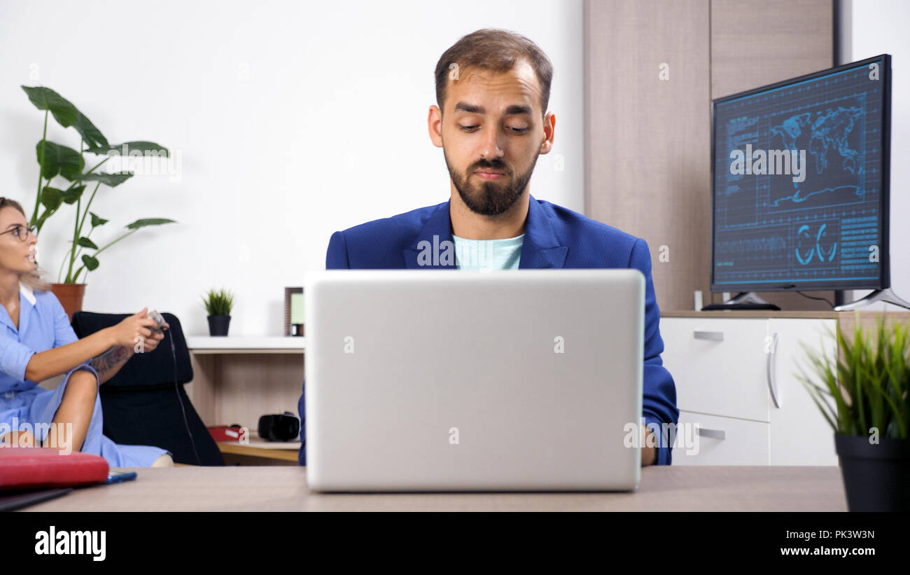 Businessman working at home on the computer while his wife is playing ...