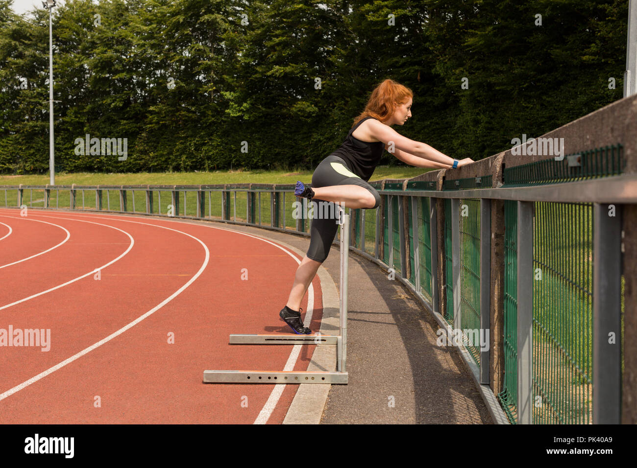 Female athlete exercising on railing at sports track Stock Photo - Alamy