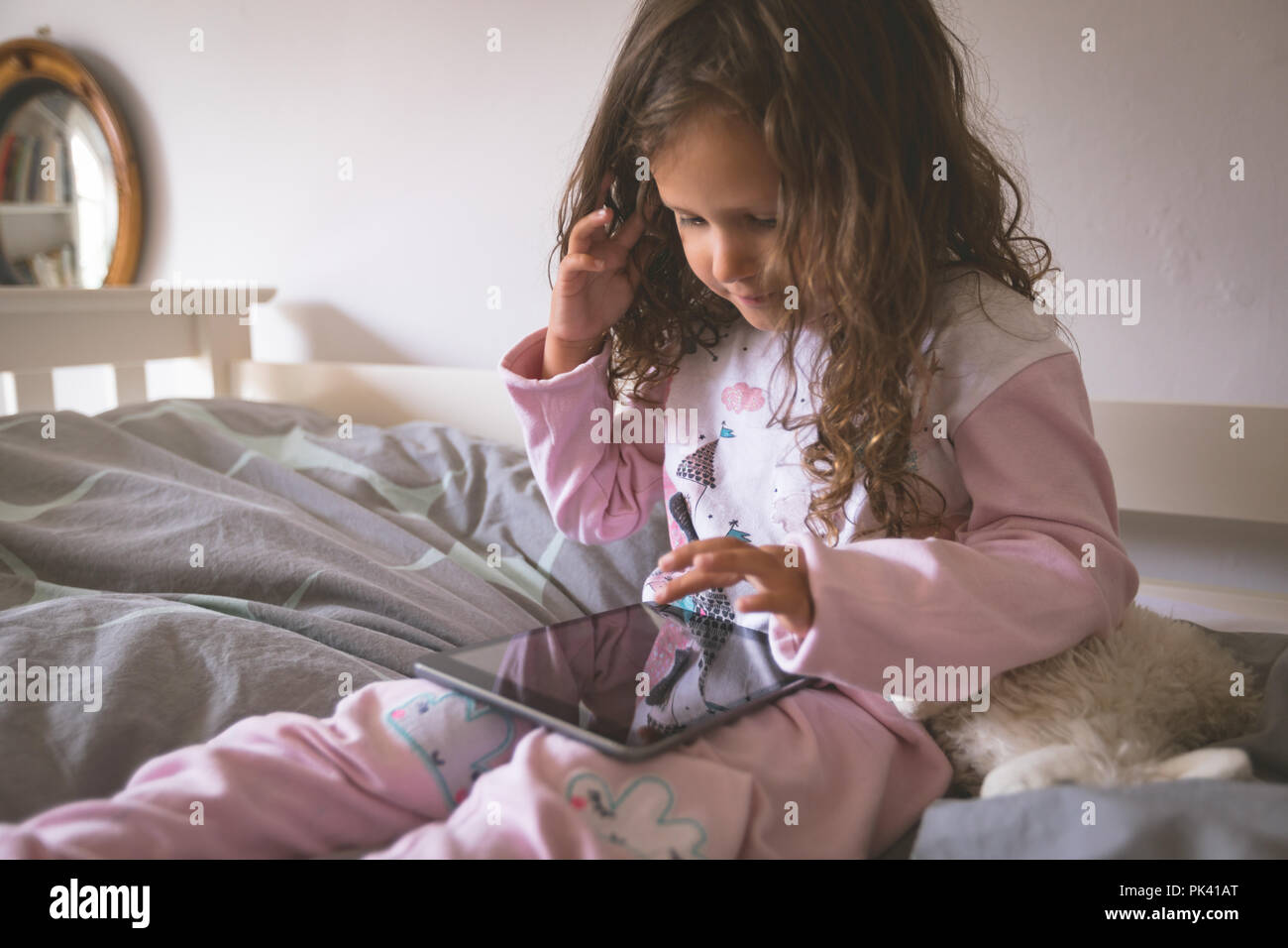 Girl using digital tablet on bed in bedroom Stock Photo - Alamy
