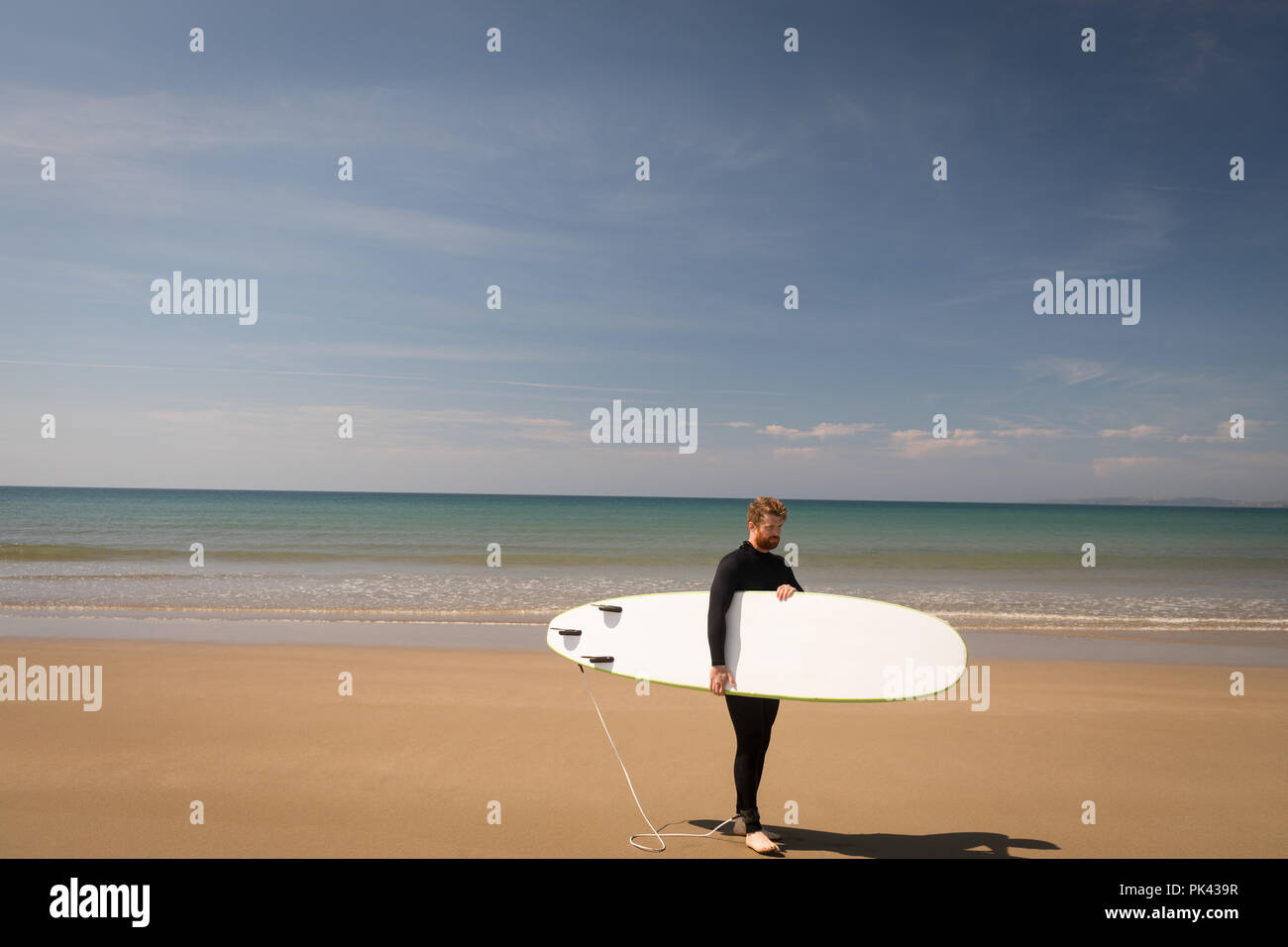 Surfer with surfboard standing at beach Stock Photo - Alamy