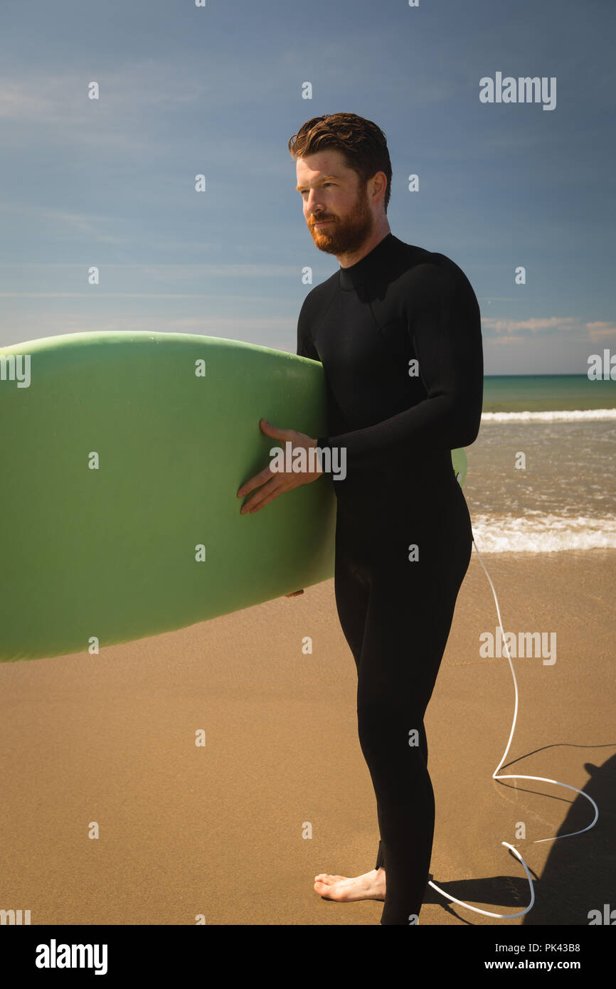Surfer with surfboard standing at beach Stock Photo - Alamy