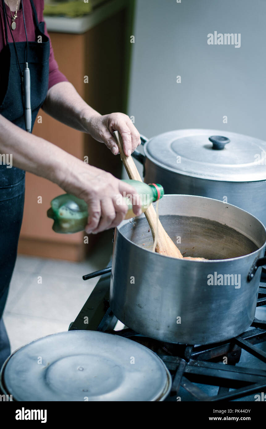 Hand of a woman adding ingredients to the pot where the food is cooking ...