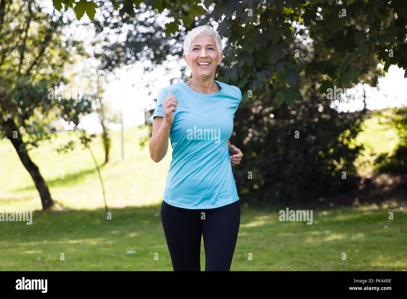 Front view of senior woman jogging through park Stock Photo - Alamy
