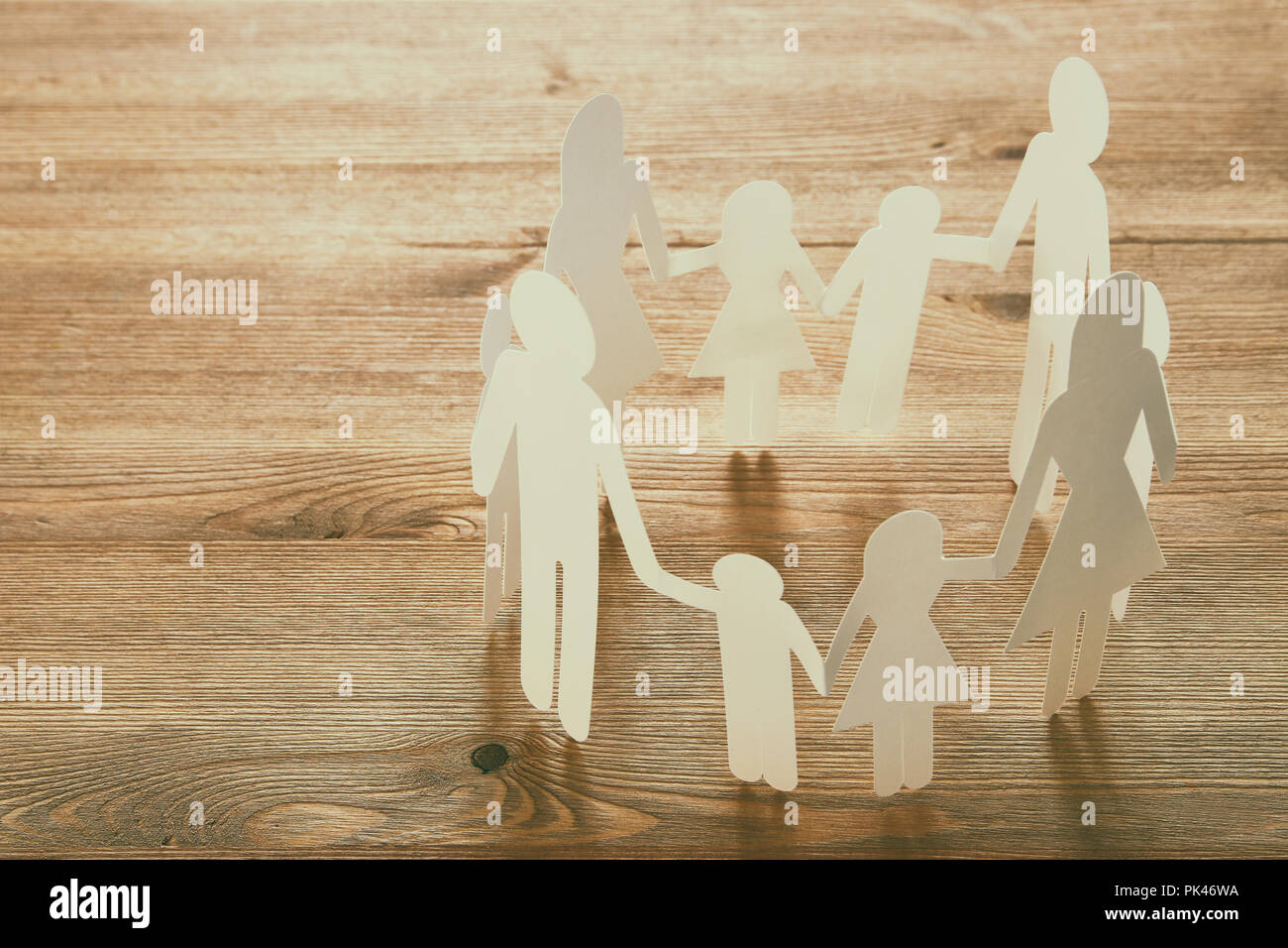 concept image of Family paper chain cutout holding hands, over wooden ...