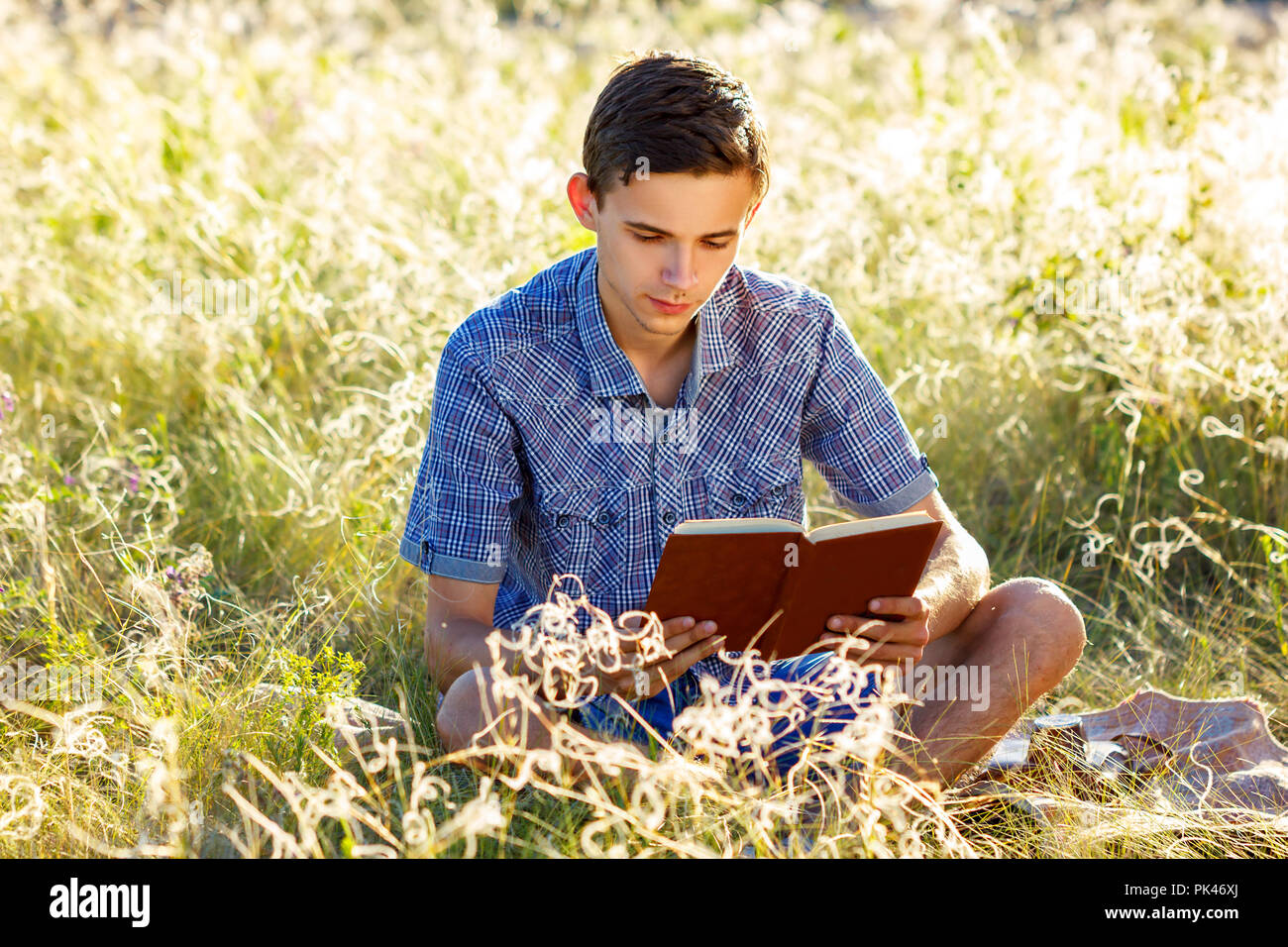 young man sitting in nature reading a book Stock Photo - Alamy